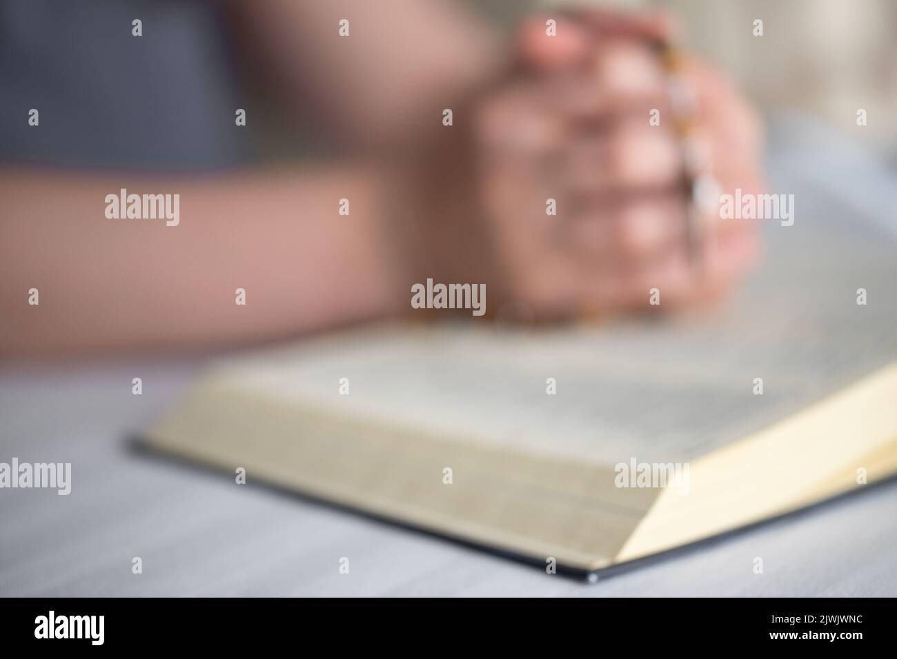 female hands folded in prayer on a Holy Bible. Blurred background Stock ...