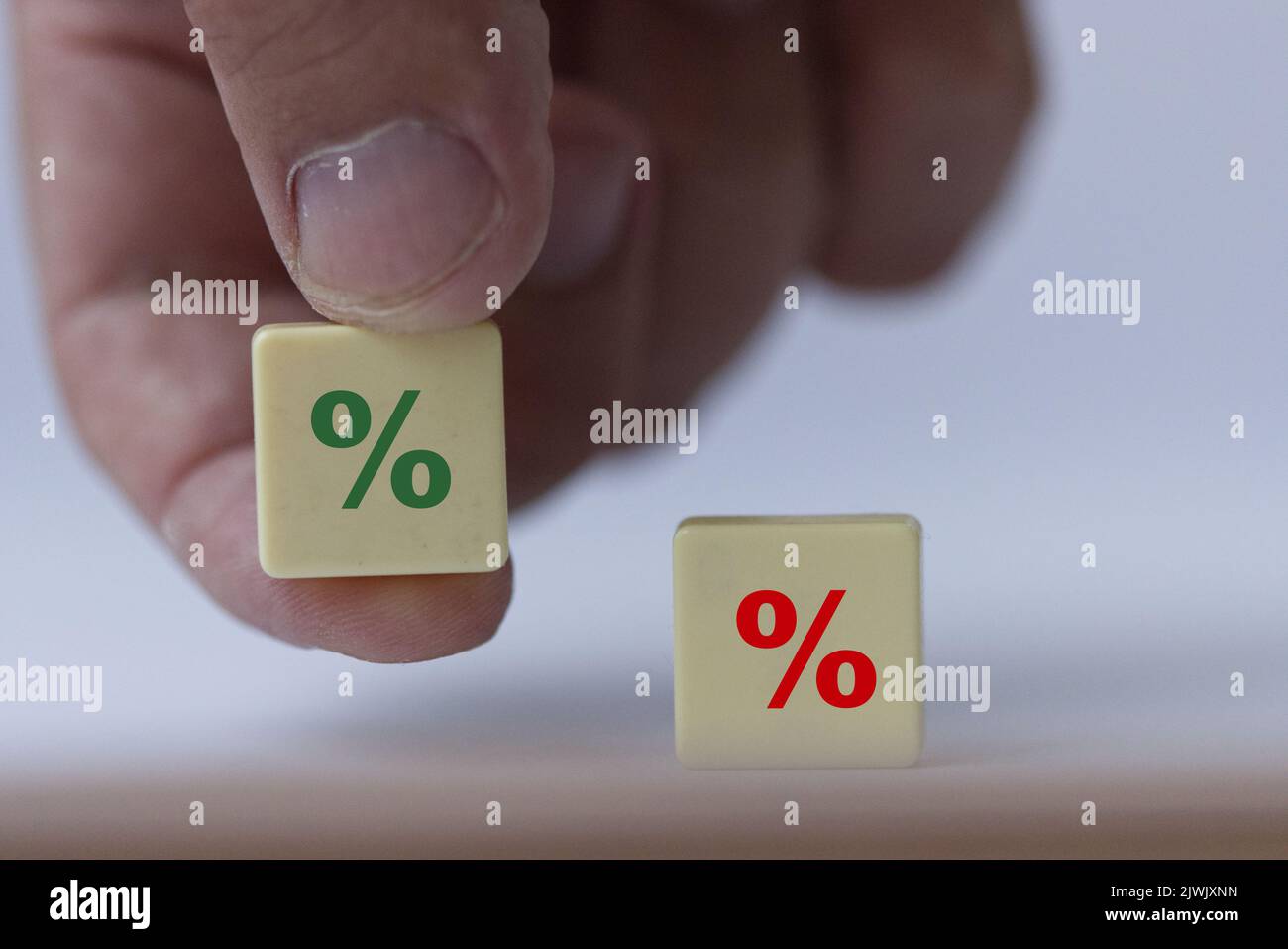 Hand is holding a piece of scrabble with green percentage sign ...