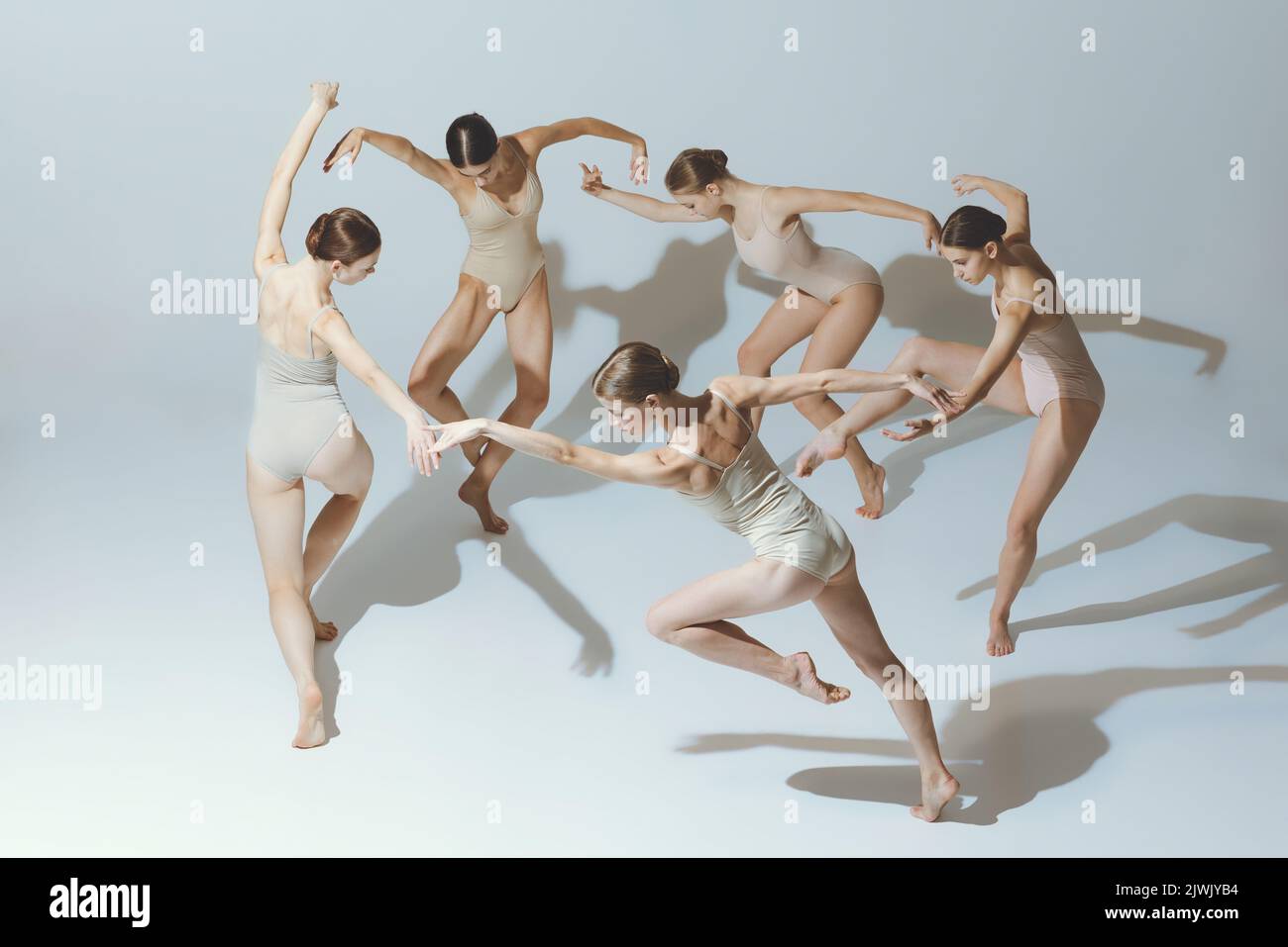 Group of young girls, ballet dancers performing, posing isolated over grey studio background ...