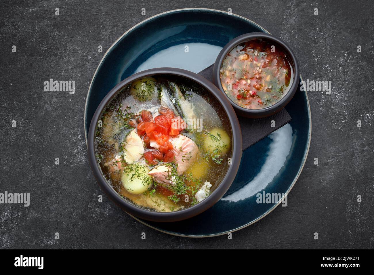 Salmon fish soup with spicy vegetable sauce, on a dark background Stock ...