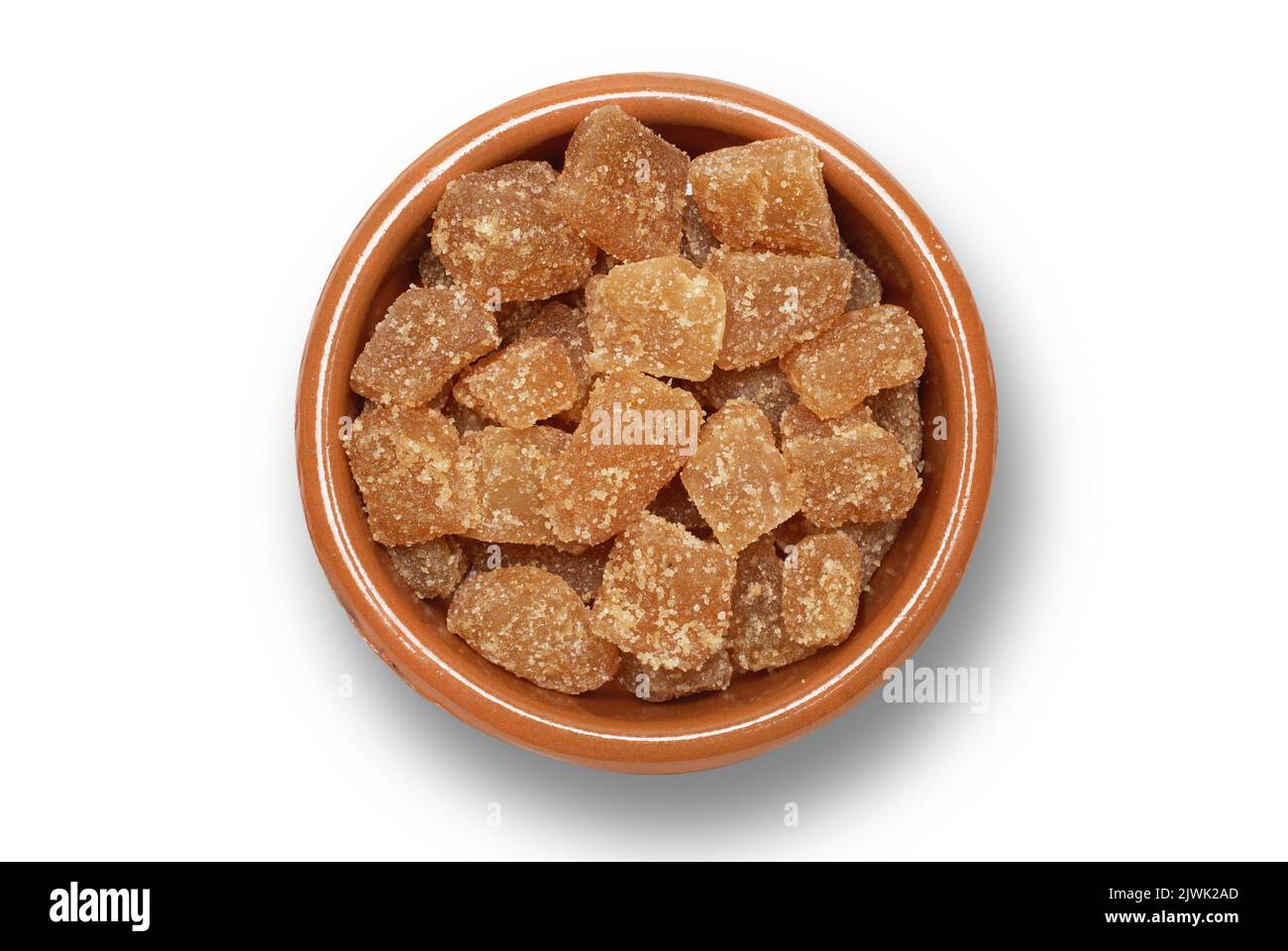 Chunks of crystallized ginger in a brown bowl. Shot from overhead ...