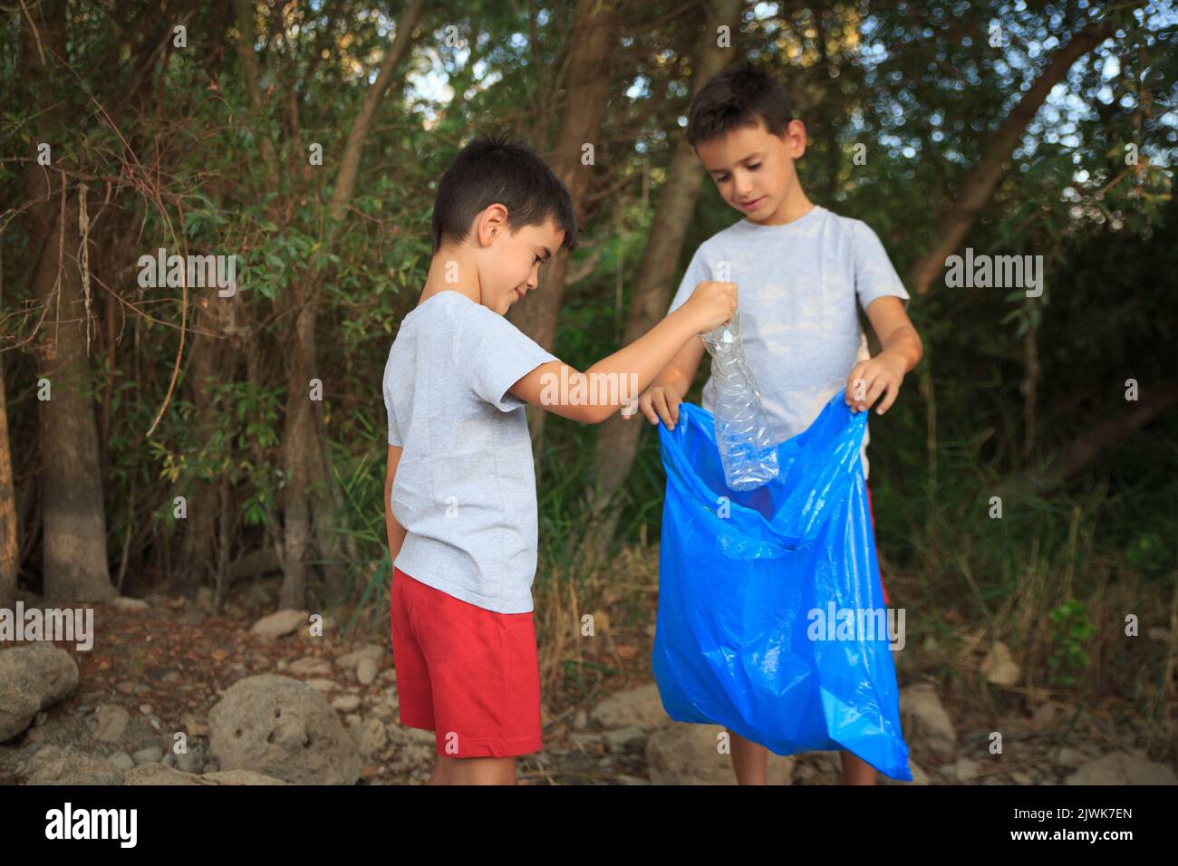 two children collect garbage in the forest. Recycling and nature care ...
