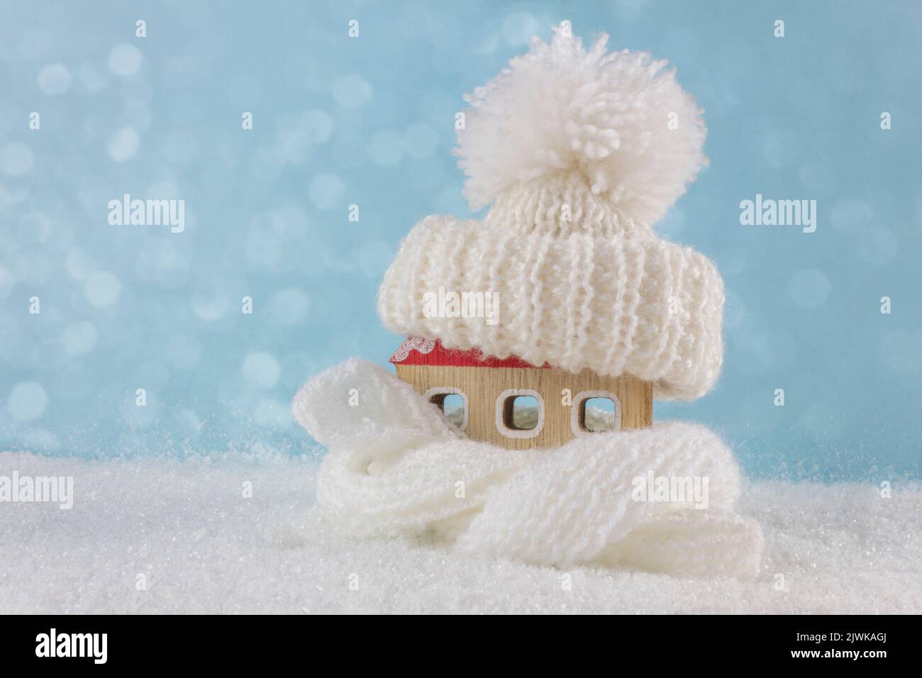 Figure of house and warm clothes on the snow against blurred lights ...