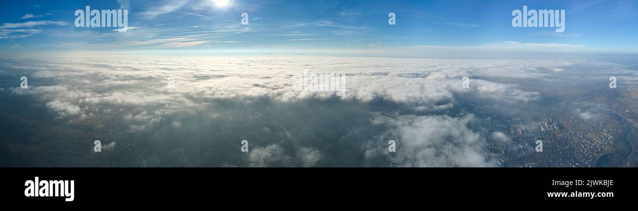 Aerial view from high altitude of distant city covered with puffy ...