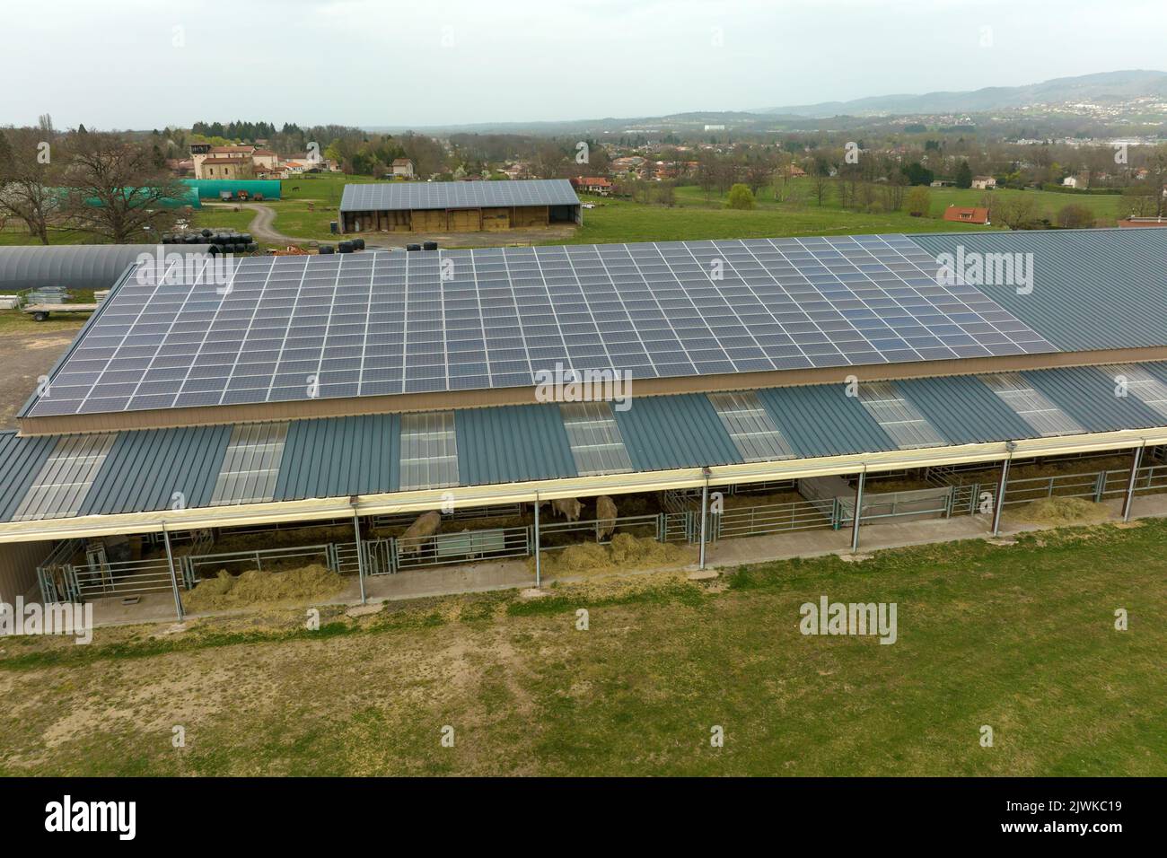 Aerial view of blue photovoltaic solar panels mounted on farm building ...