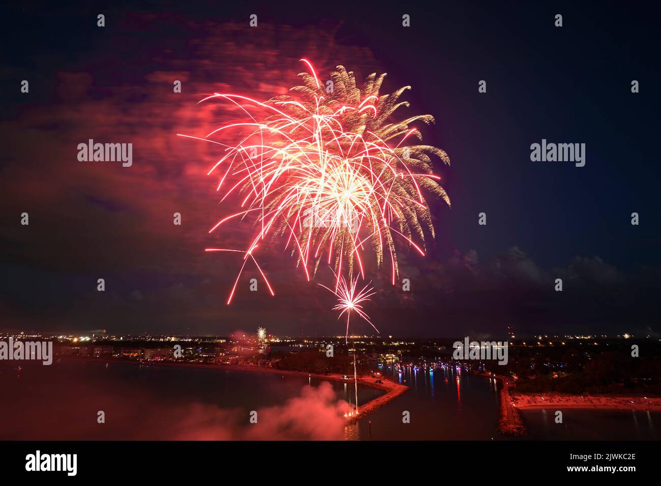 Aerial view of bright fireworks exploding with colorful lights over sea ...