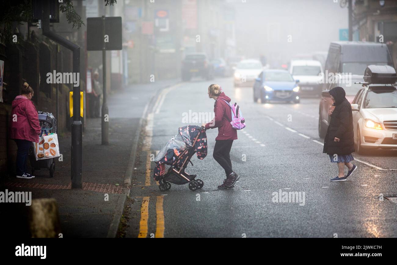 A woman with a pram and a older lady cross the road in Queensbury, West ...