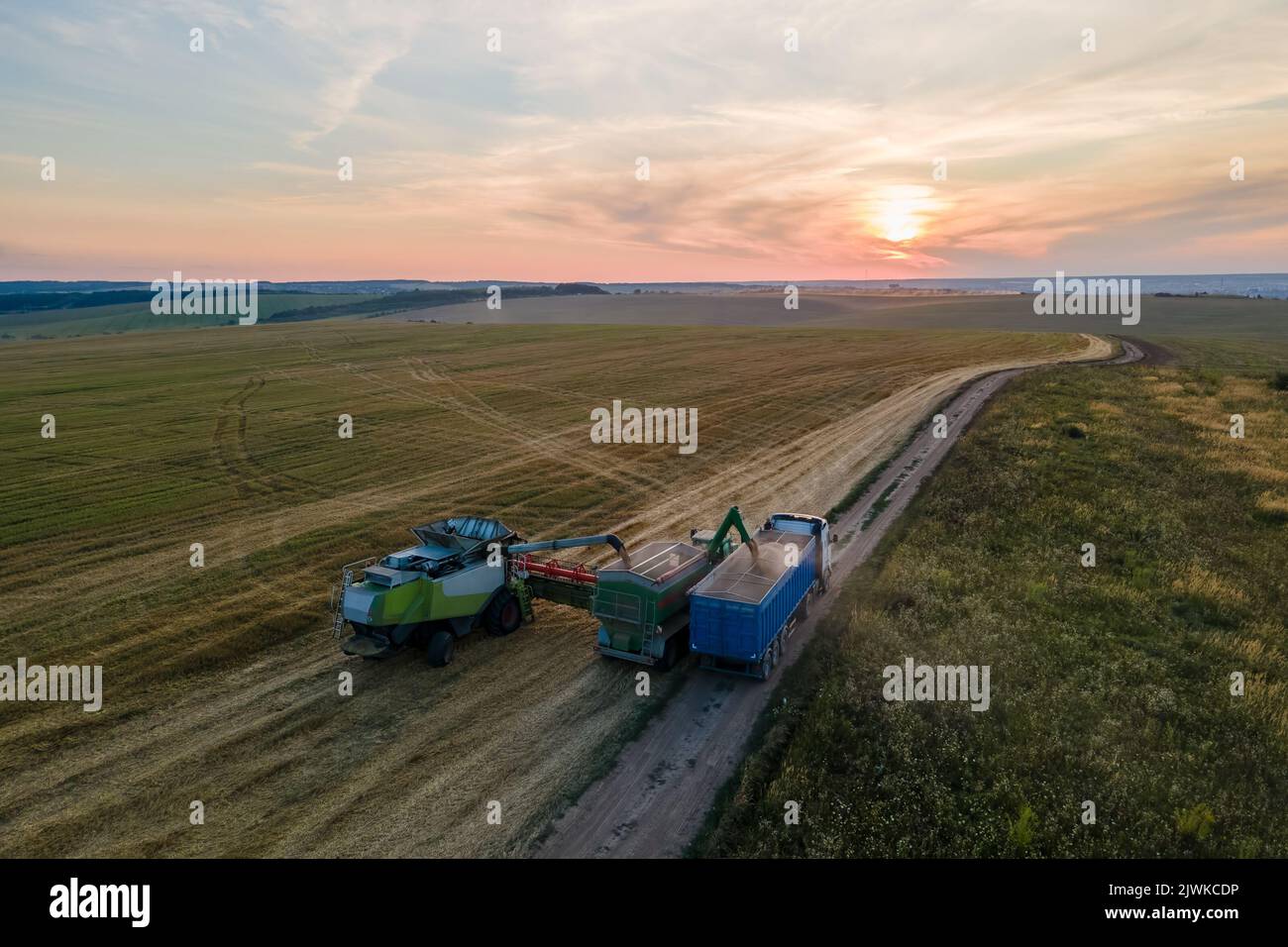 Aerial view of combine harvester unloading grain in cargo trailer ...