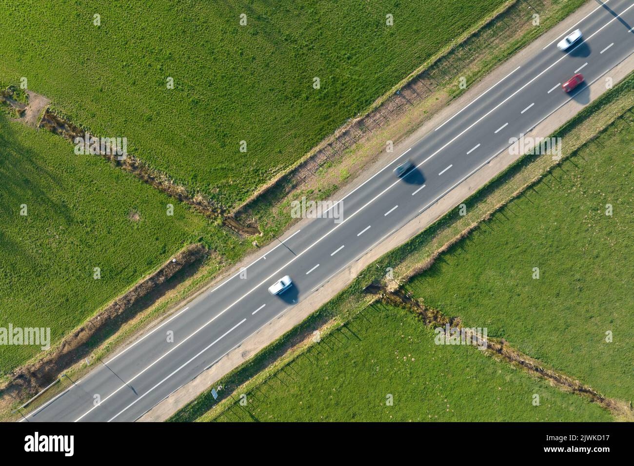 Aerial view of intercity road between green agricultural fields with ...