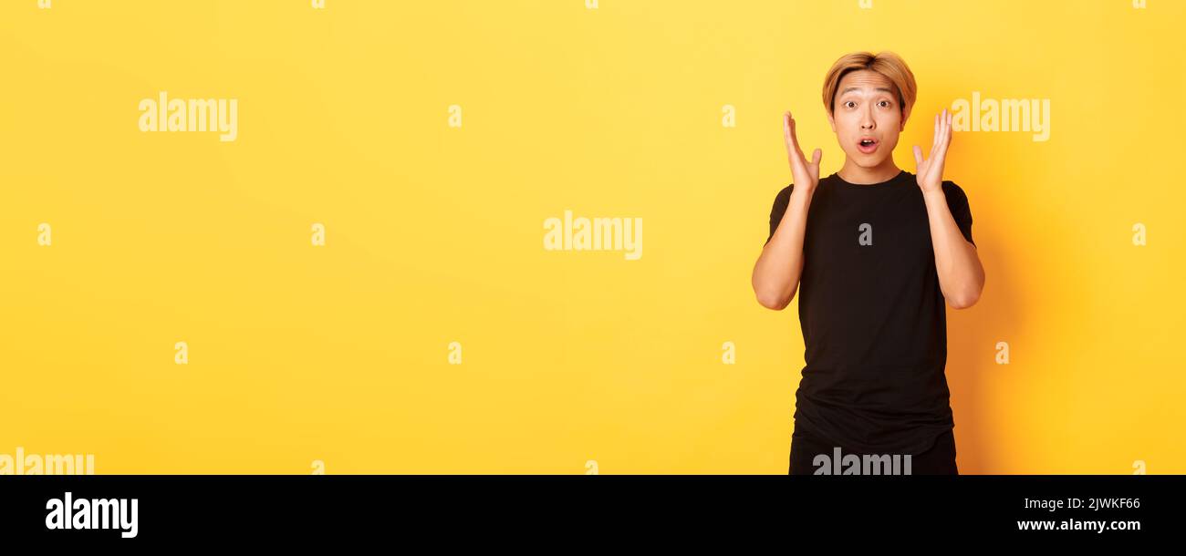 Portrait of surprised gasping blond asian guy reacting to awesome news ...