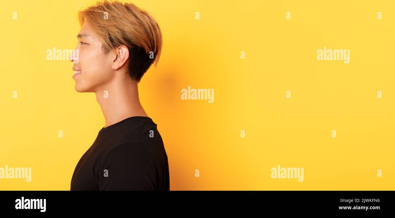 Profile of stylish handsome asian guy with fair hair looking left and ...