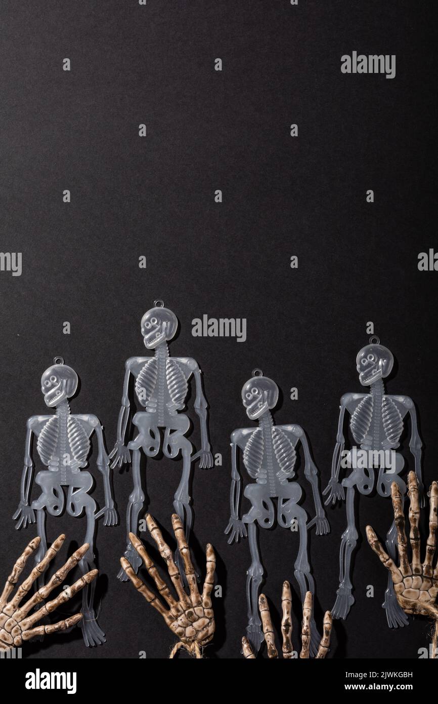 Multiple skeleton toys and skeleton hands with copy space on grey ...