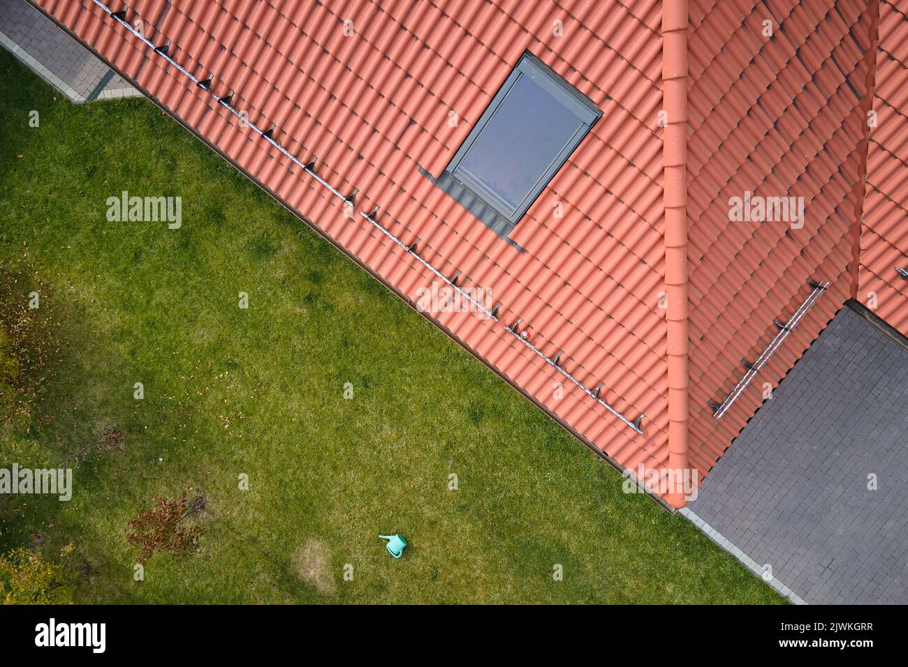 Closeup of attic window on house roof top covered with ceramic shingles ...