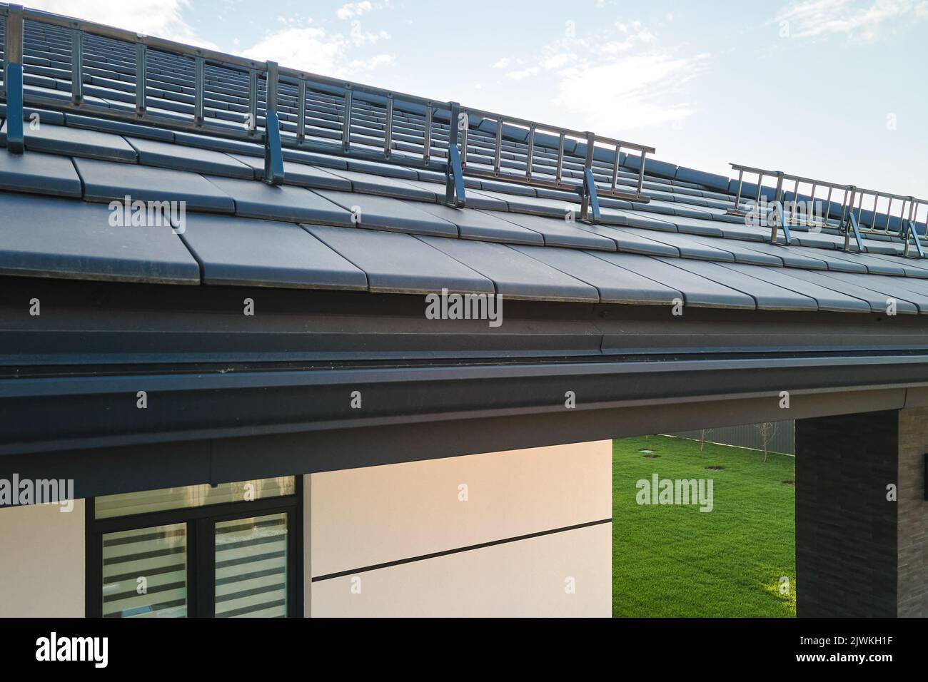 Closeup snow guard for safety in winter on house roof top covered with ...