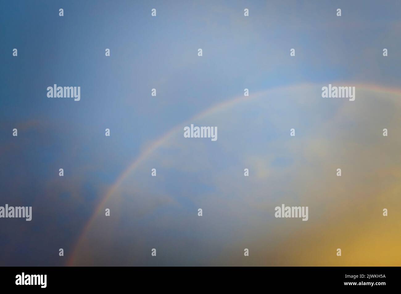 Colorful round rainbow against blue evening sky after heavy ...