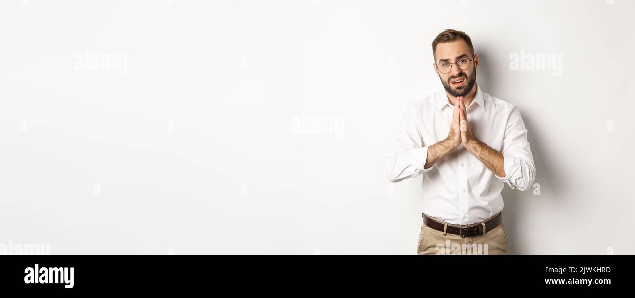 Worried man asking for help, begging for favour, standing over white ...