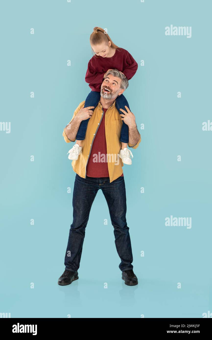 Little Daughter Sitting On Dad's Shoulders Posing Over Blue Background ...