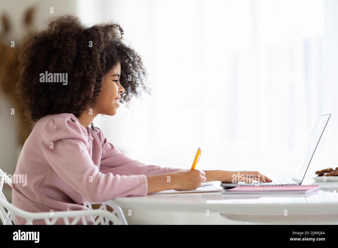 Smiling african american girl typing on laptop keyboard, side view ...