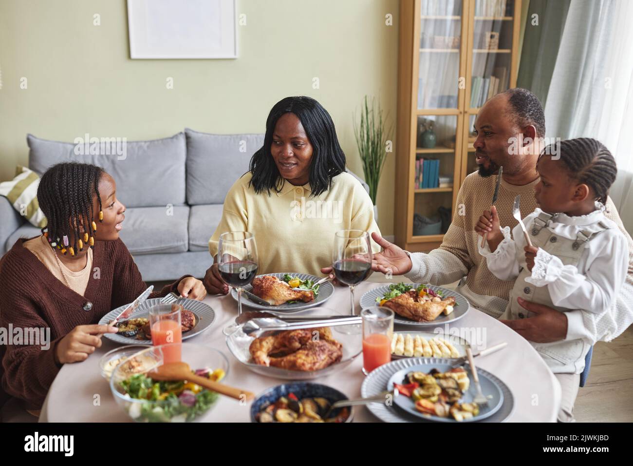 African family of four talking to each other while having dinner at ...