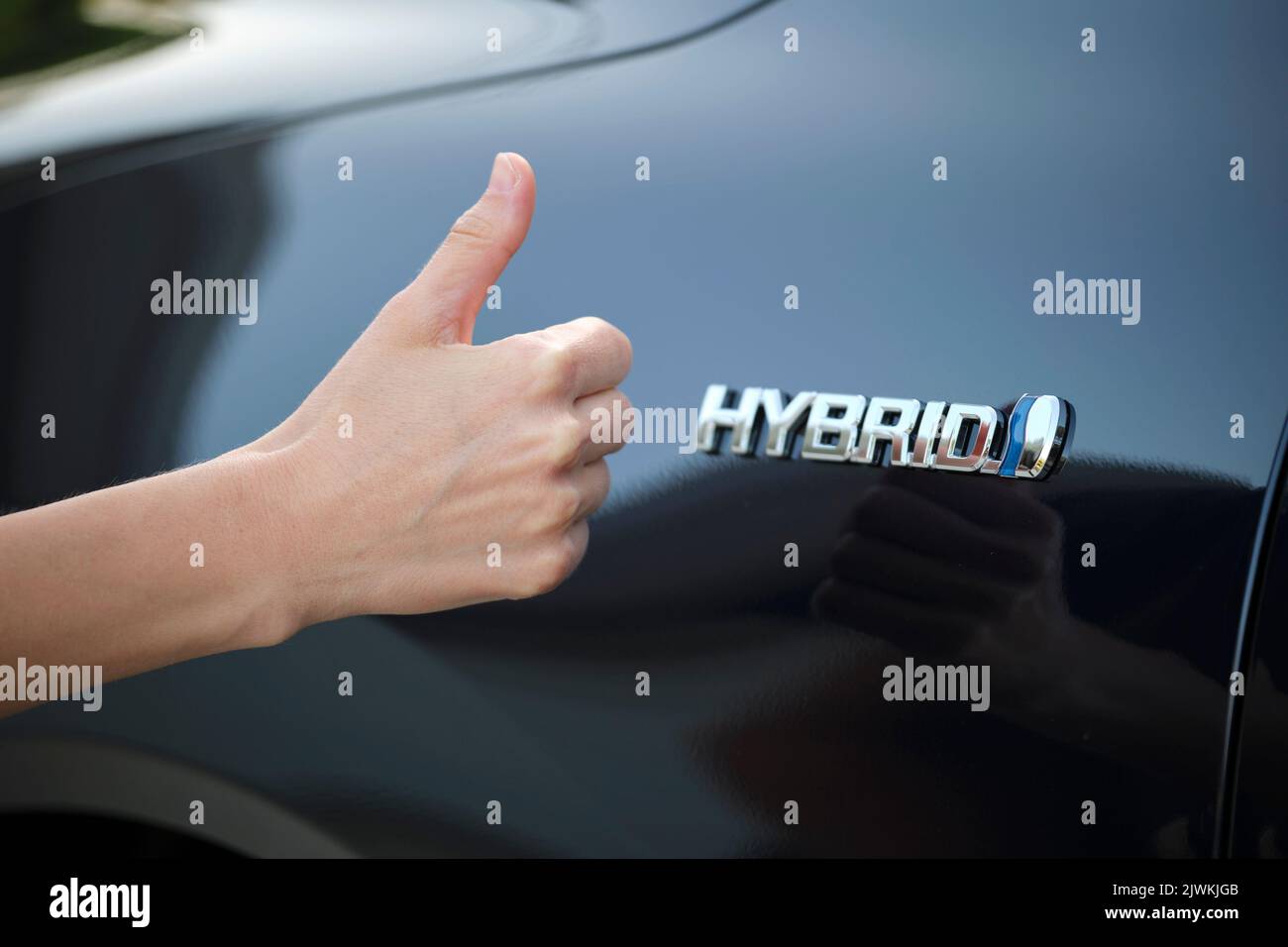 Purchaser hand showing thumb up sign at hybrid car new effective ...