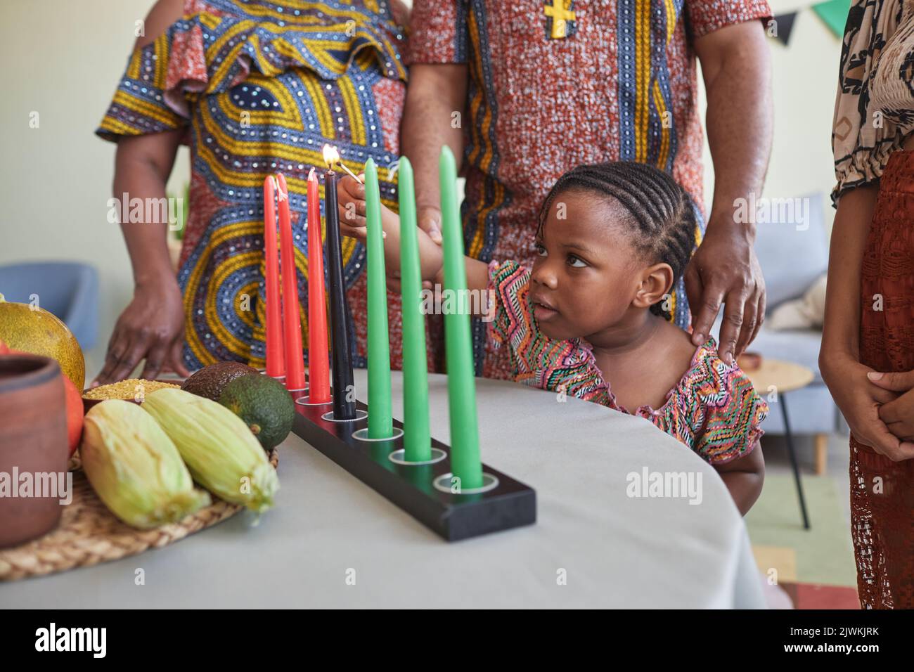 African little girl lighting candles on table while celebrating Kwanzaa ...