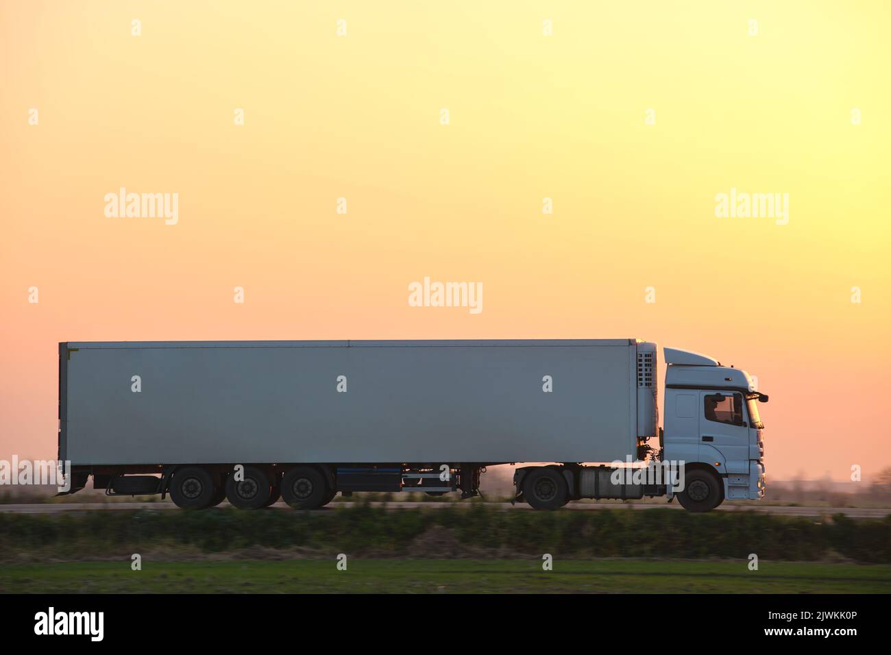 Semi-truck with cargo trailer driving on highway hauling goods in evening. Delivery ...