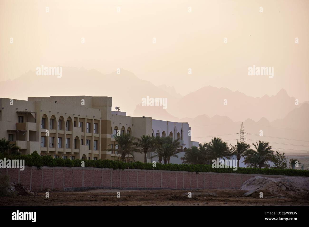 Sunset landscape with remote hotel complex against dark mountain peaks ...