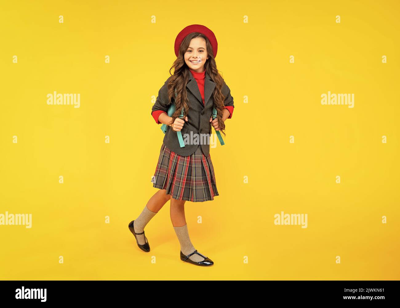 happy kid in school uniform with beret and backpack walk on yellow ...