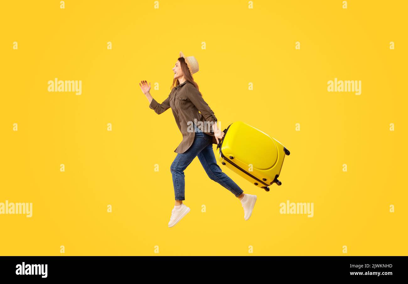 Female Tourist Running In Mid Air Carrying Suitcase, Yellow Background ...