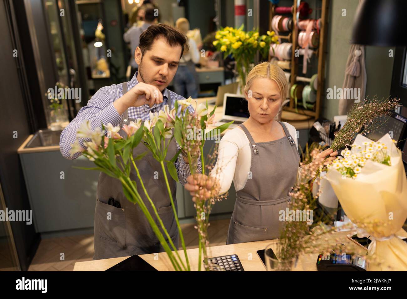 a florist and his assistant take care of fresh flowers in a bouquet ...