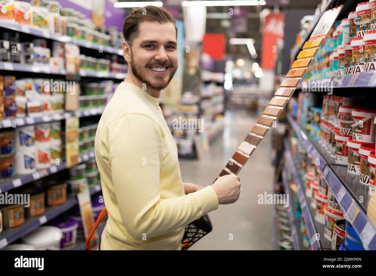 satisfied customer looking at camera at hardware store next to rows of ...