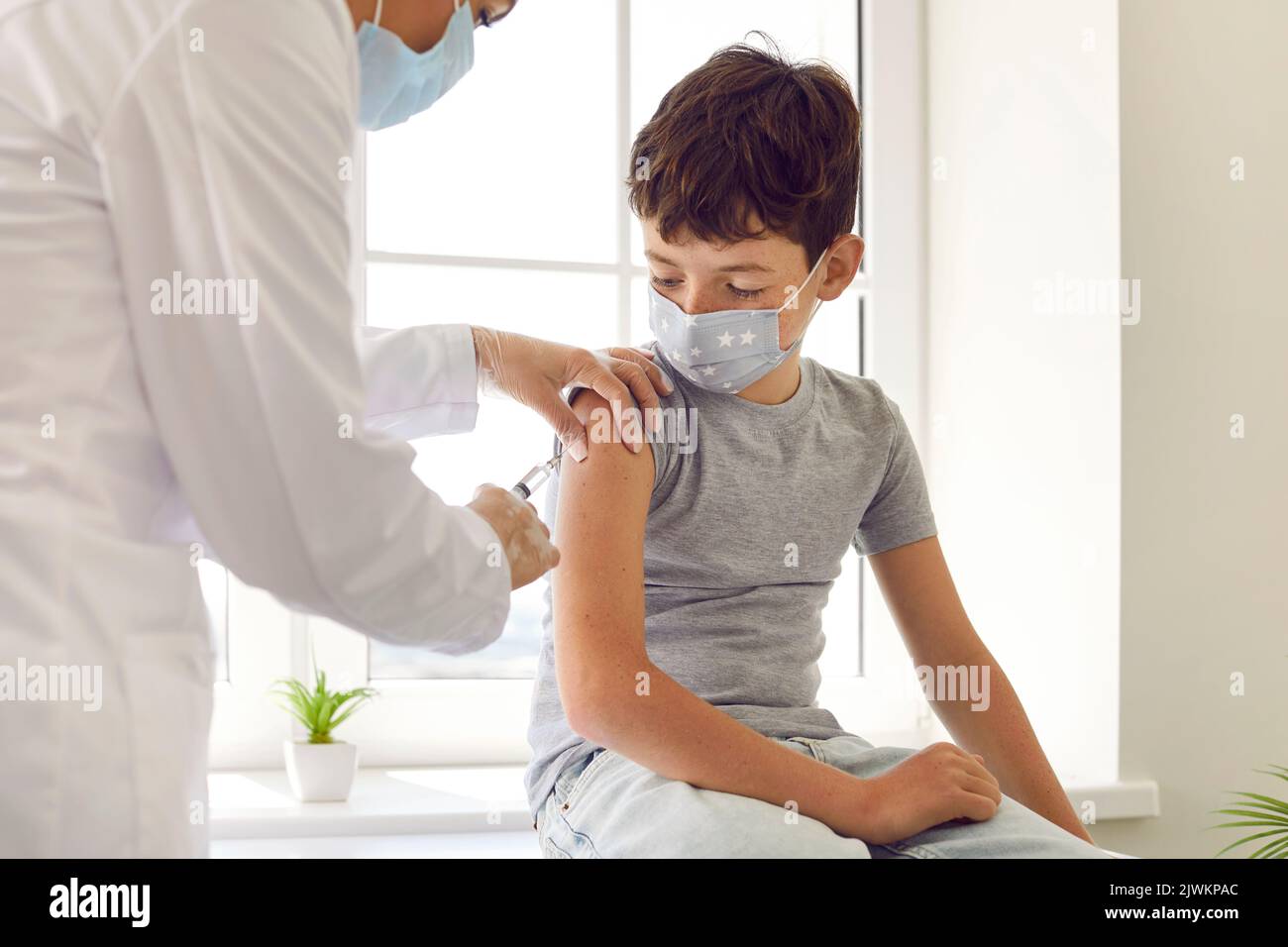 Nurse giving injection to school kid to protect him from flu, covid or ...