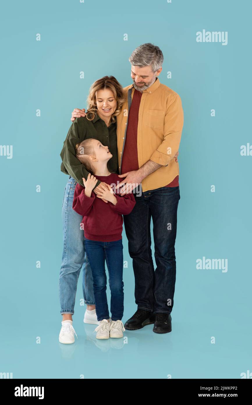 Middle Aged Parents Embracing Daughter Smiling Standing Together In ...