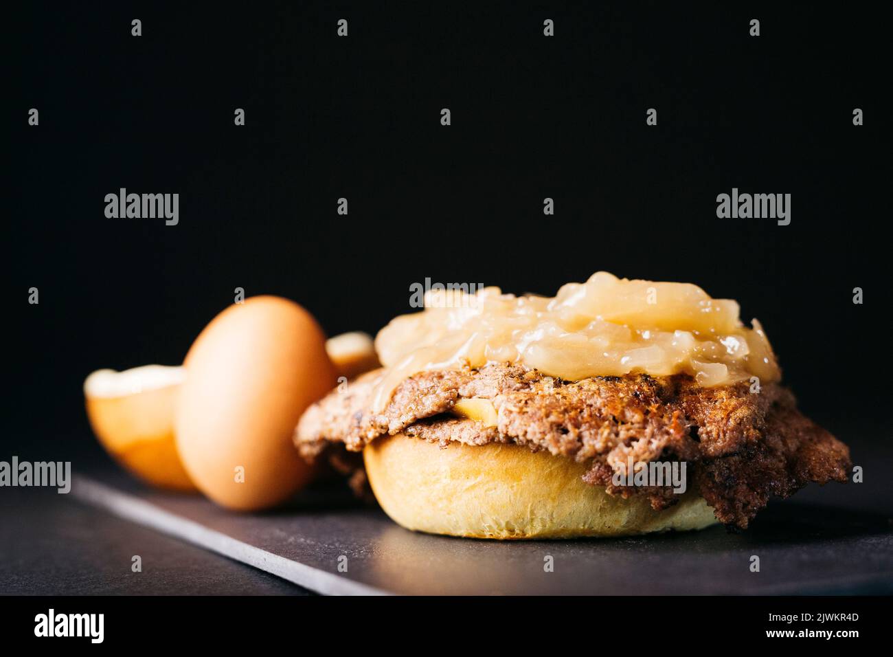 Doble smashburger with coocked onion and a boiled egg over a black ...