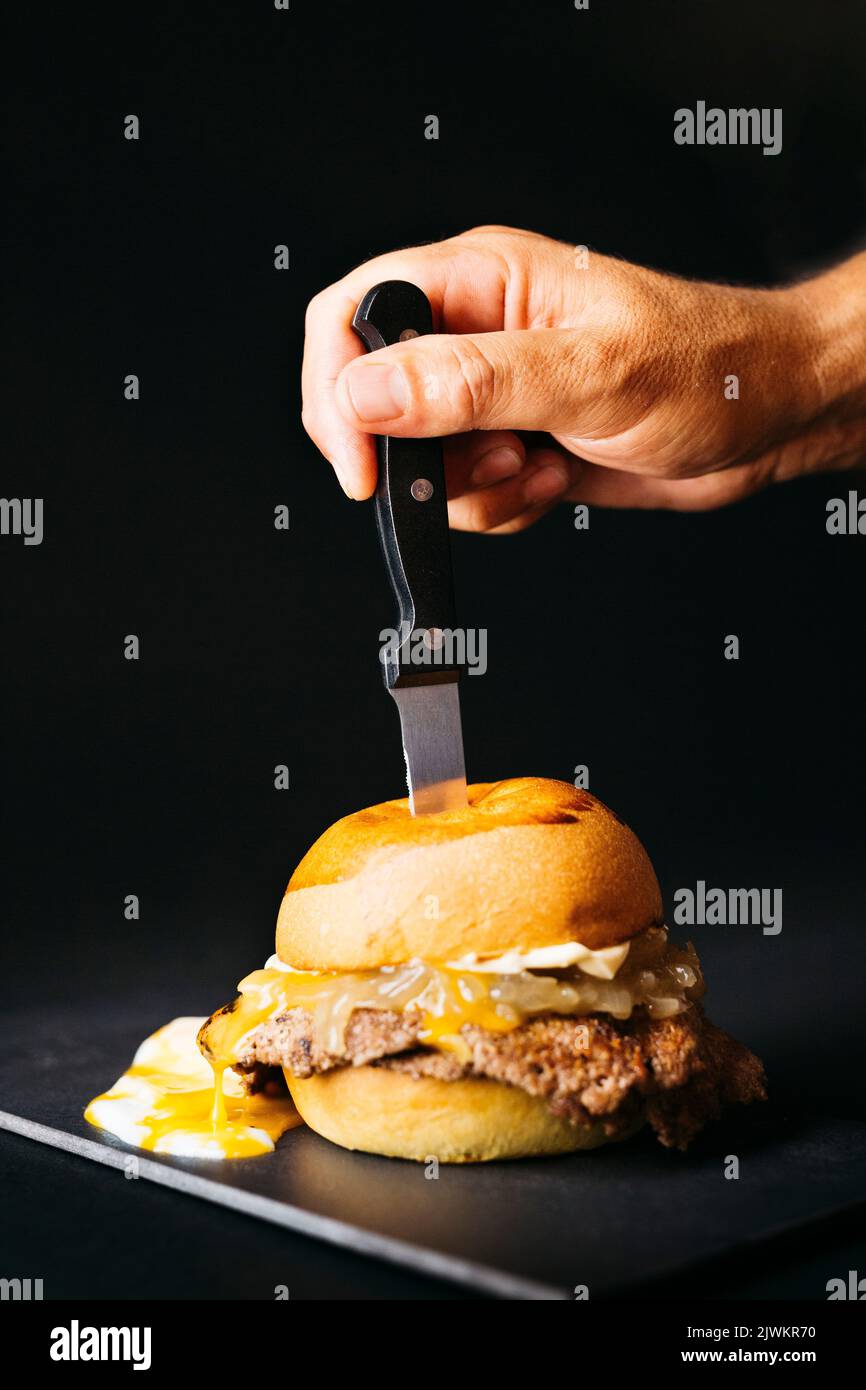 Human hand nailing a knife into a Doble smashburger with onion and a ...