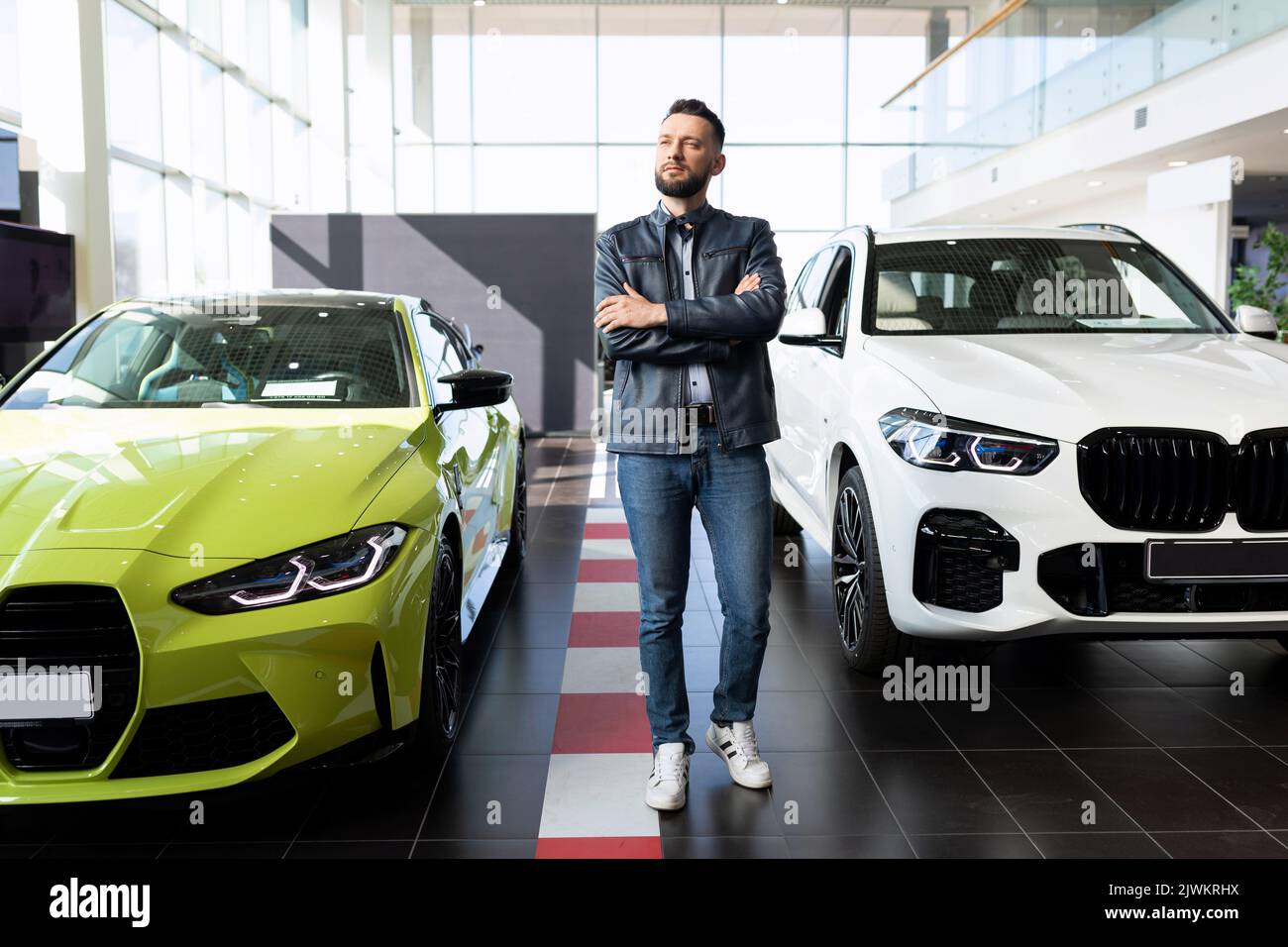 a young man stands between two sports cars in a car dealership Stock ...