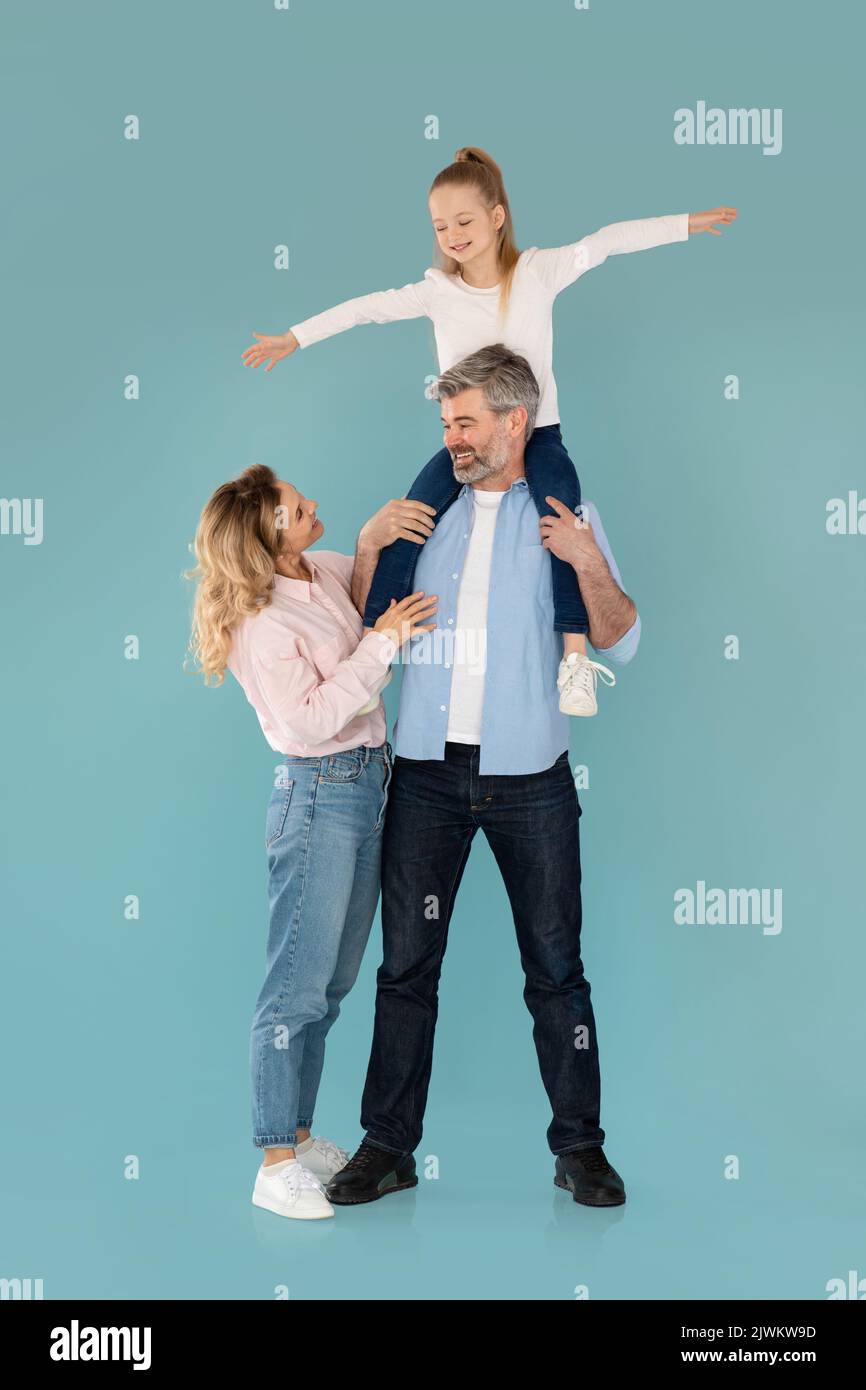 Parents And Daughter Posing, Kid Sitting On Dad's Shoulders, Studio ...