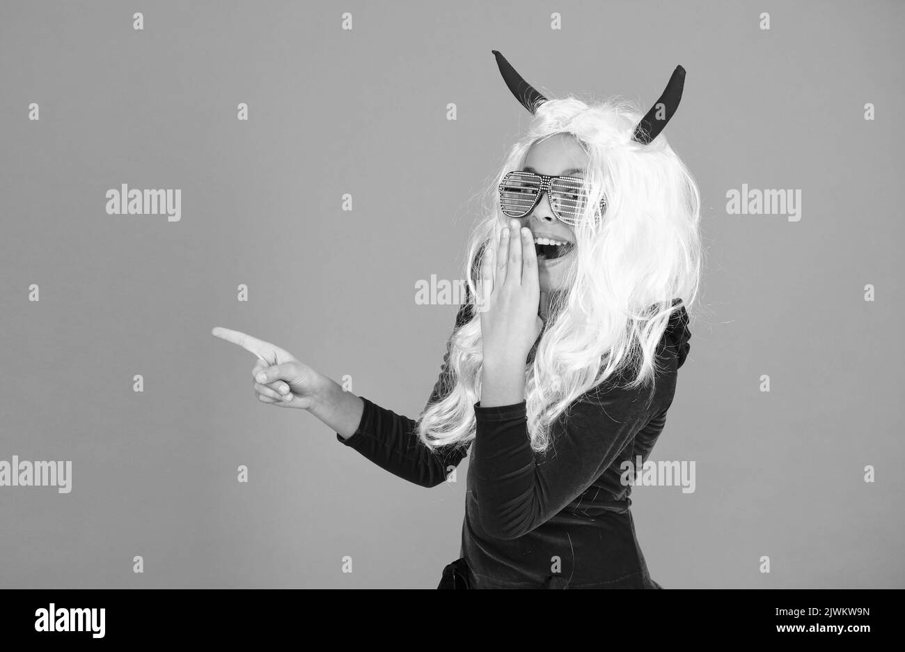 surprised devil child with party glasses and white hair wear horns ...