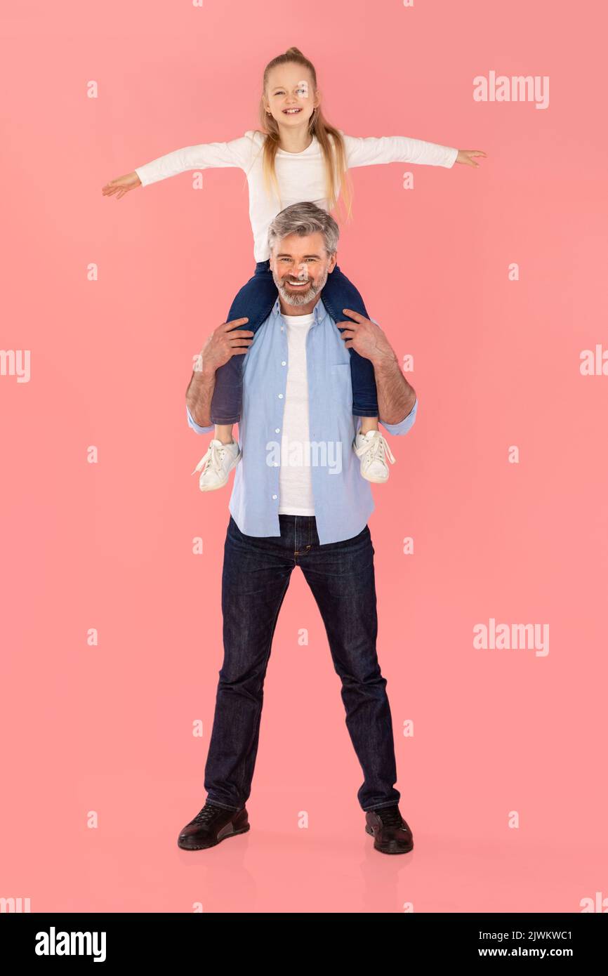 Dad Holding Child On Shoulders In Studio On Pink Background Stock Photo ...