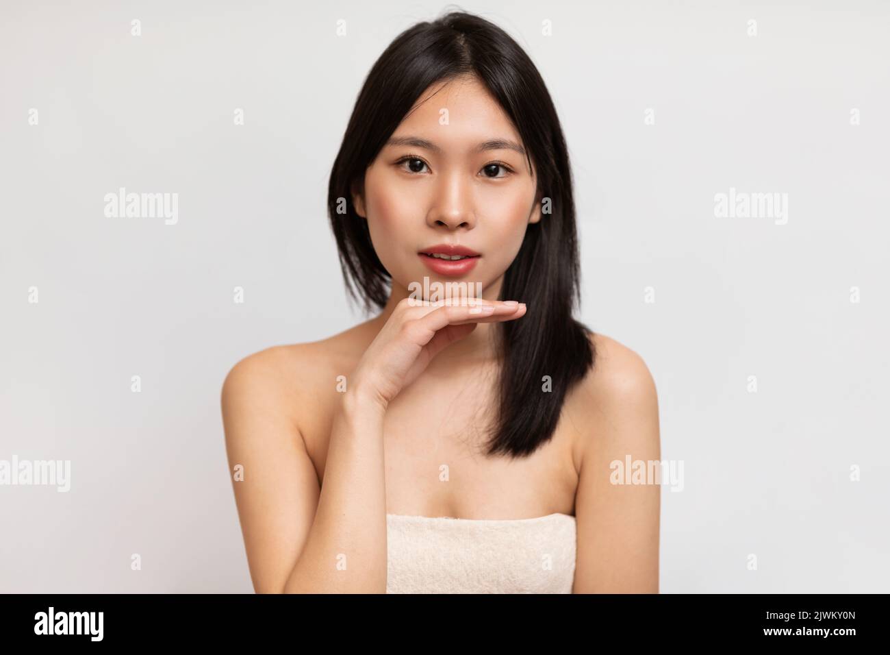 Natural beauty. Portrait of young asian lady wrapped in towel touching ...