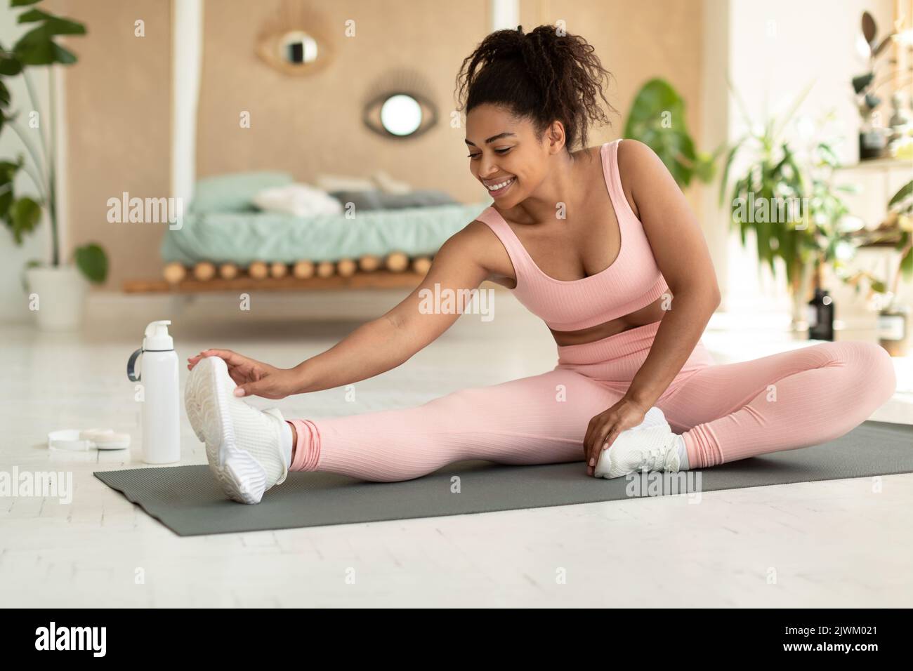 Happy black lady in sportswear exercising at home, stretching on ...