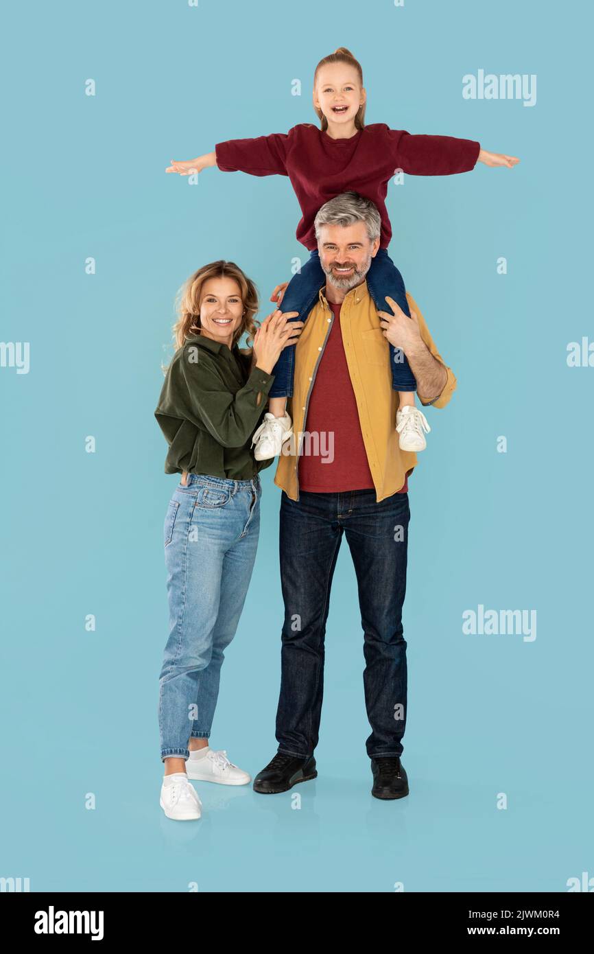 Mother And Father Posing, Holding Daughter On Shoulders, Blue ...