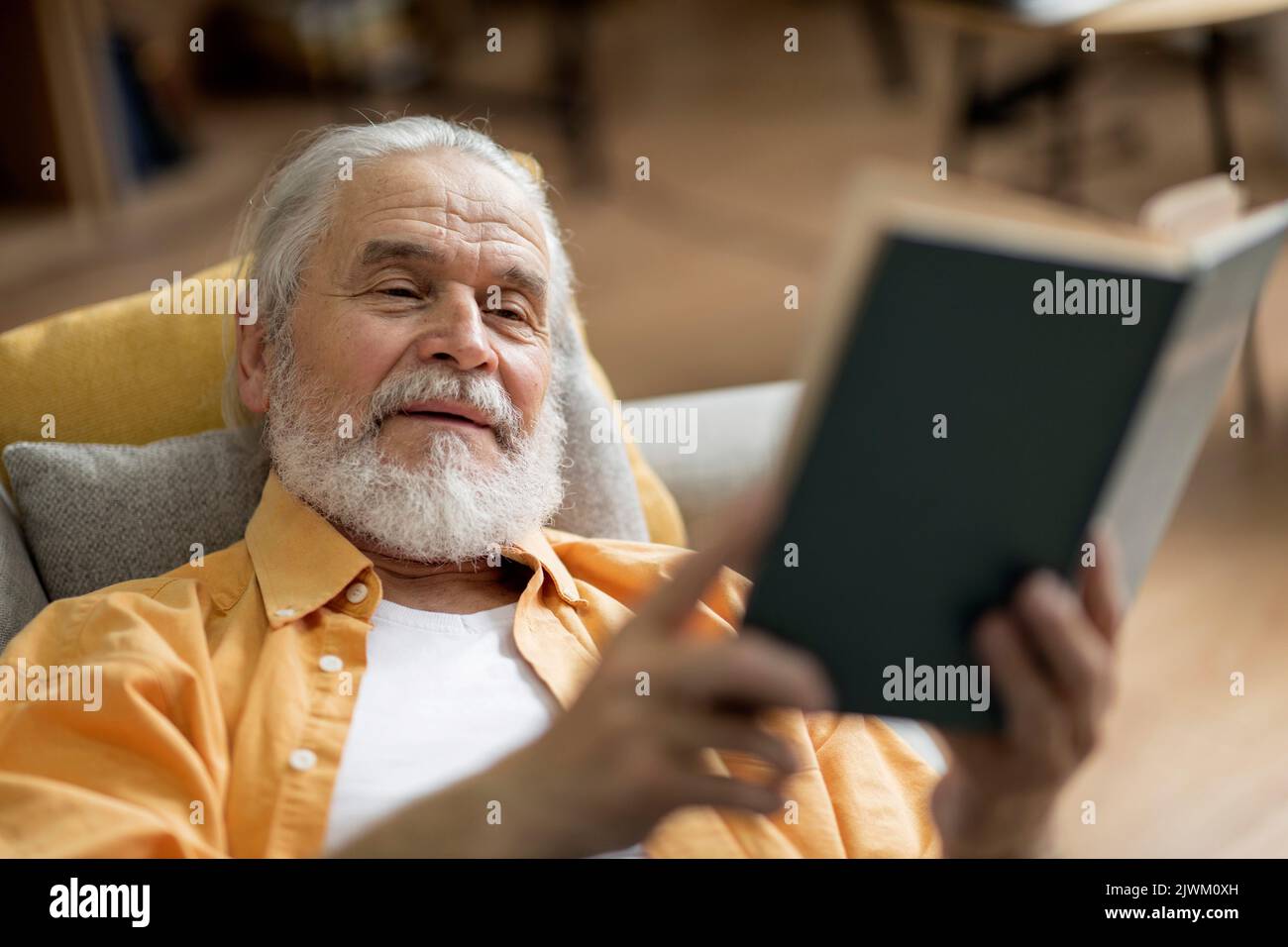 Smiling mature man home reading book hi-res stock photography and ...
