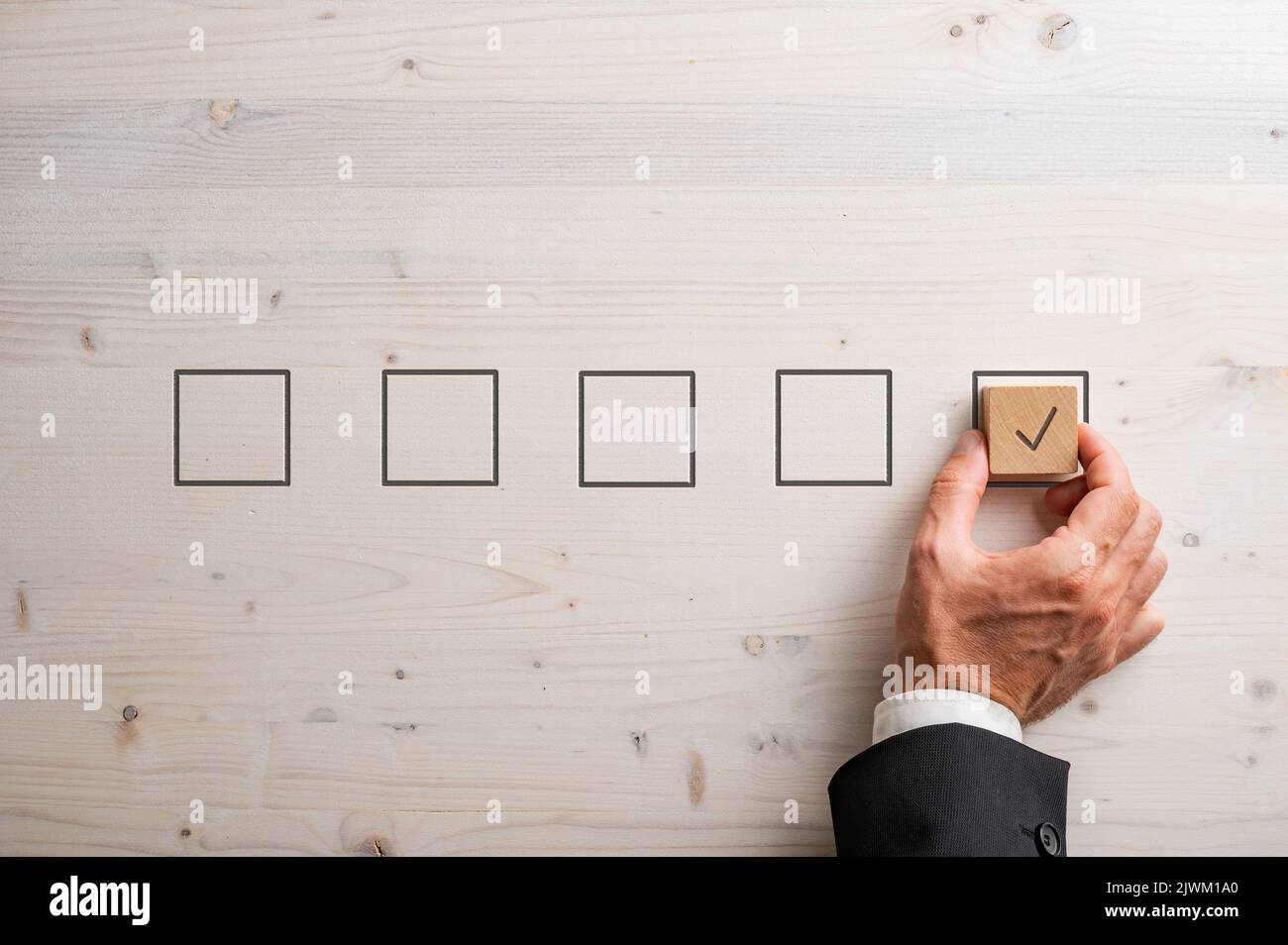 Hand of a businessman placing wooden block with a check mark on it in a ...
