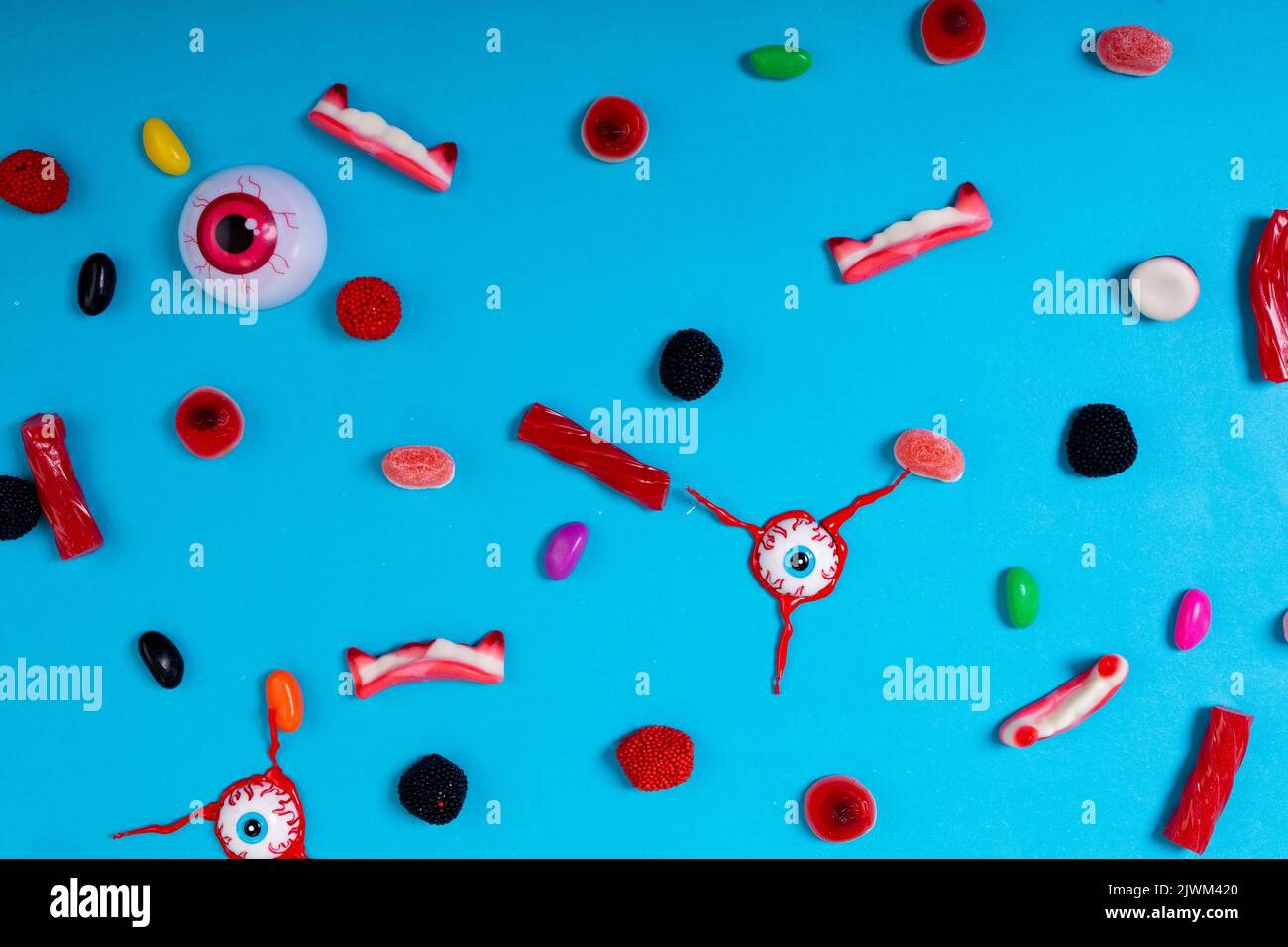 Multiple scary eyes toys and halloween candies on blue surface Stock ...