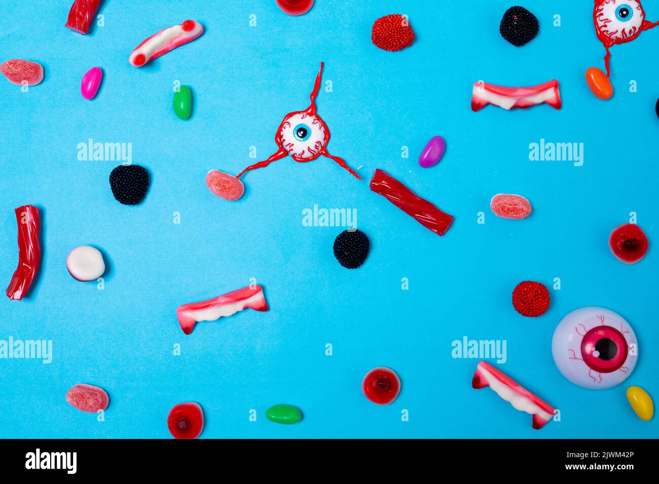 Multiple scary eyes toys and halloween candies on blue surface Stock ...