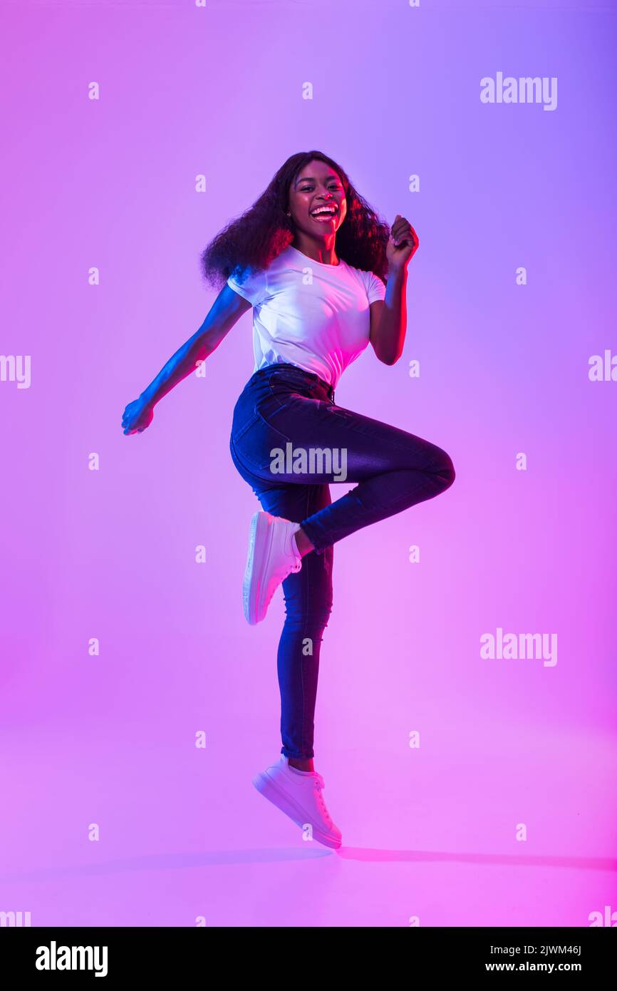 Joyful millennial African American woman flying in air, jumping ...