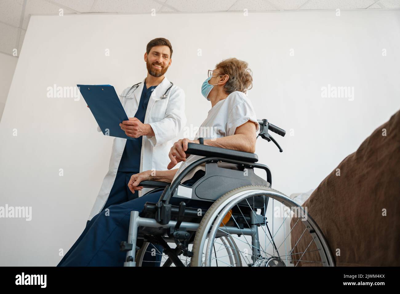 Doctor inuniform explaining to a sick patient in a wheelchair the ...