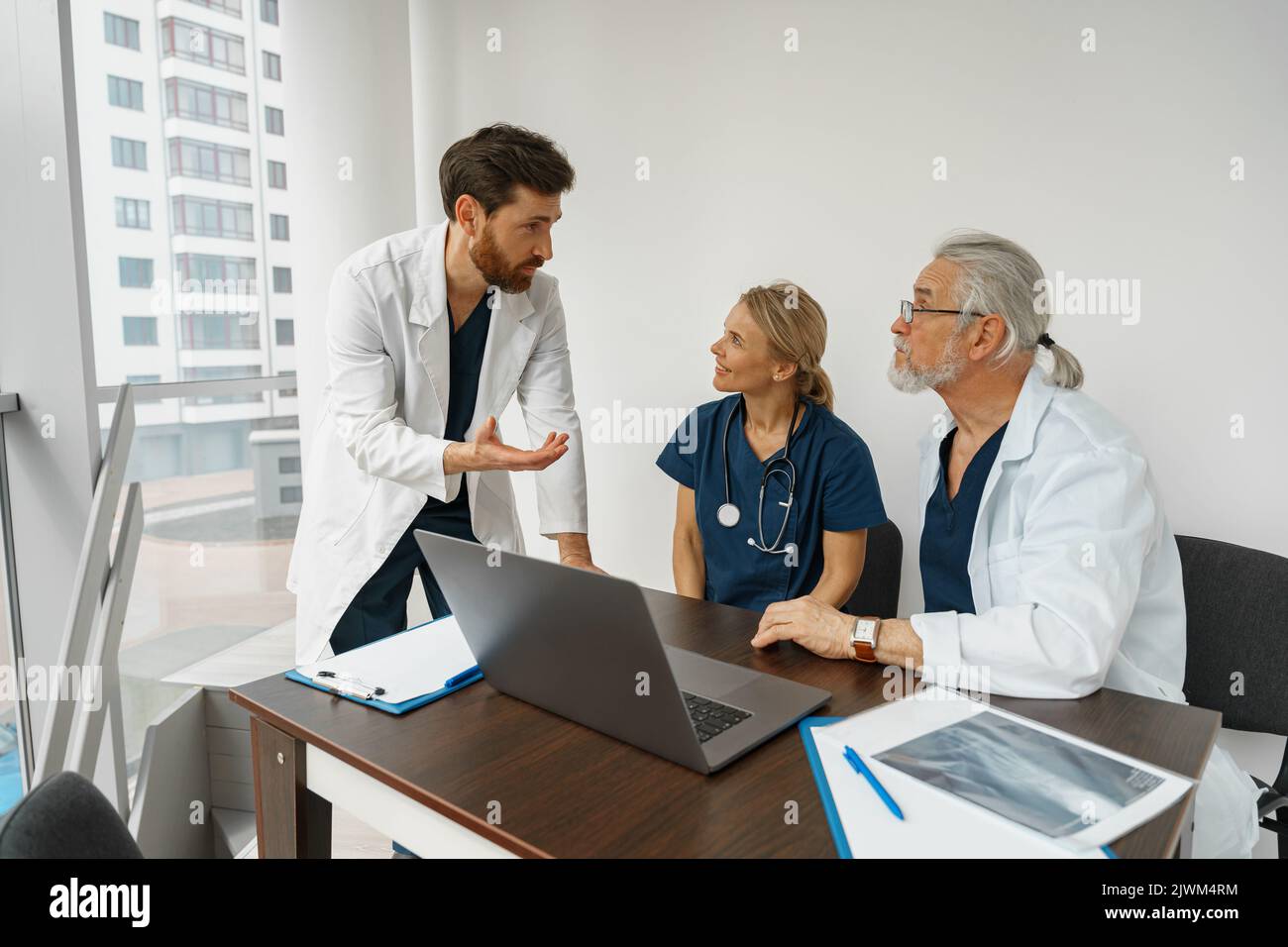 Group of doctors sitting at meeting table in conference room during ...