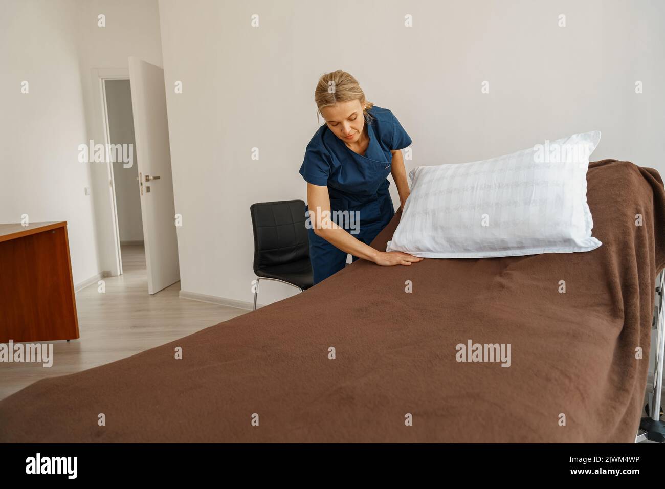 Medical nurse preparing hospital ward bed with pillow and blanket for ...